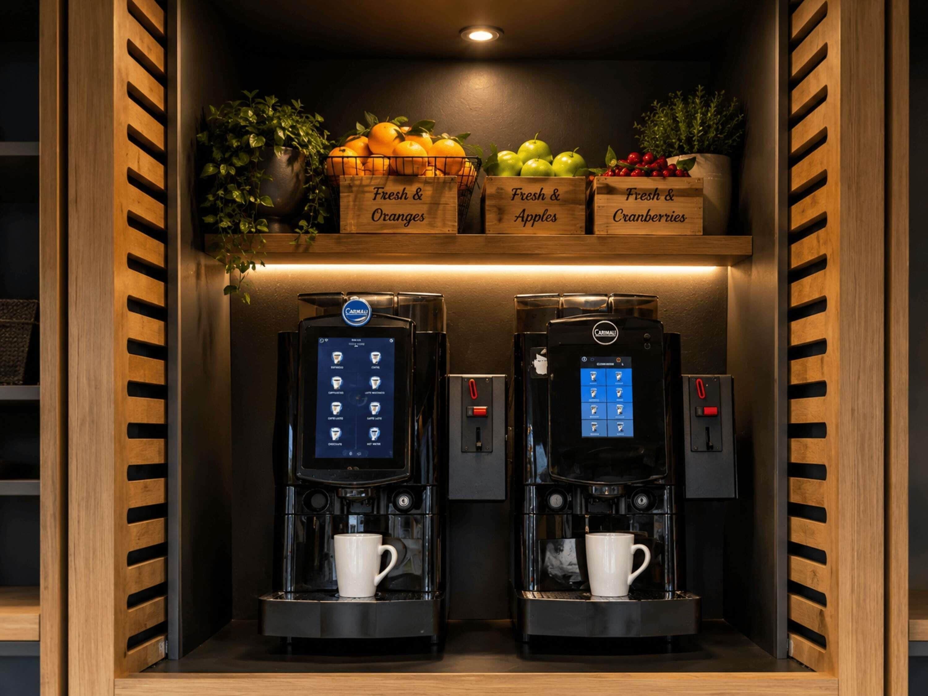 Uma estação de café com duas máquinas de expresso e uma seleção de frutas frescas.