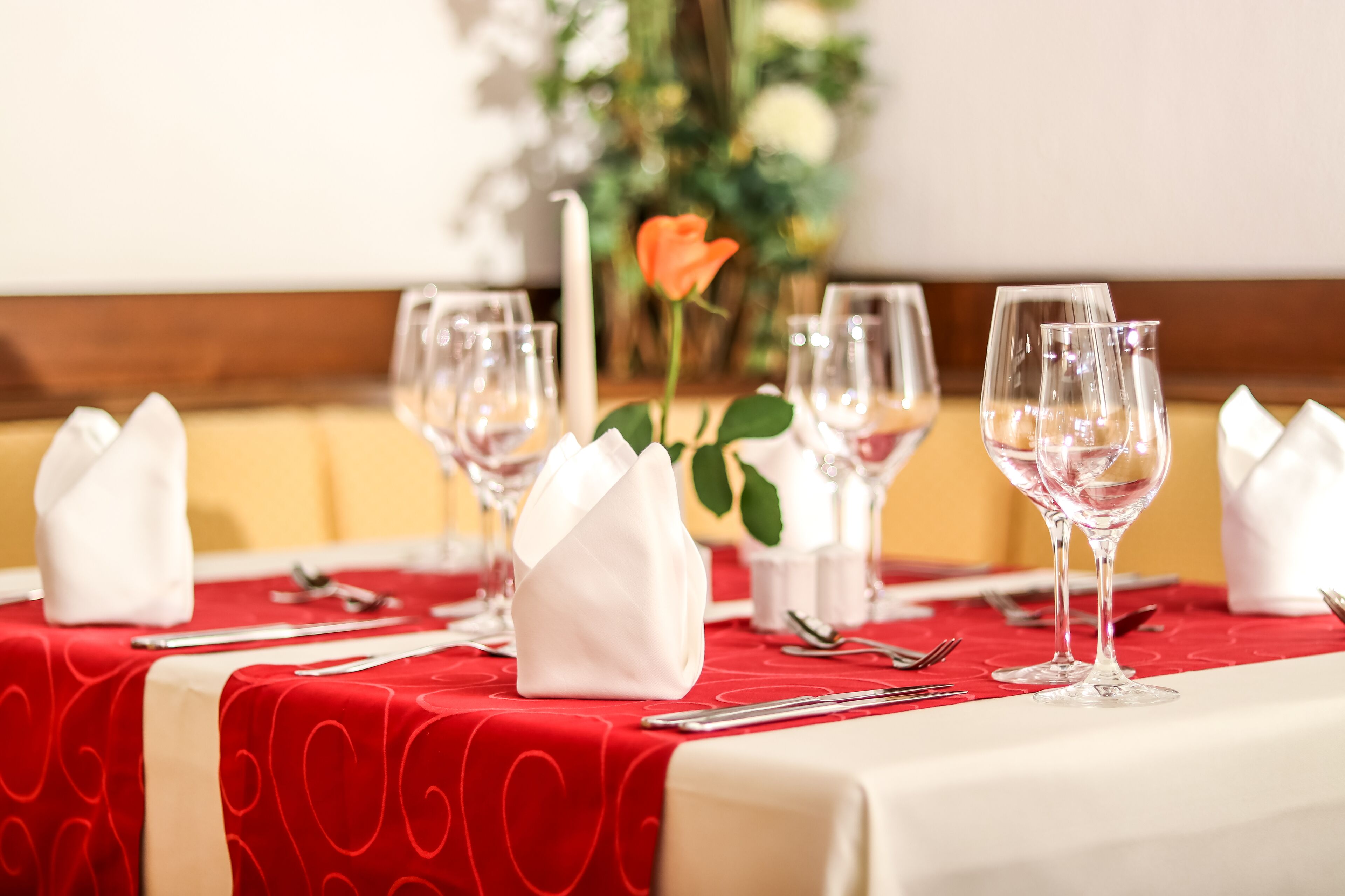 Mesa posta para refeição com guardanapos brancos, copos de vinho e talheres.