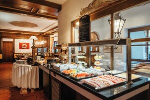 Uma área de buffet com diversos alimentos e um cardápio em lousa.