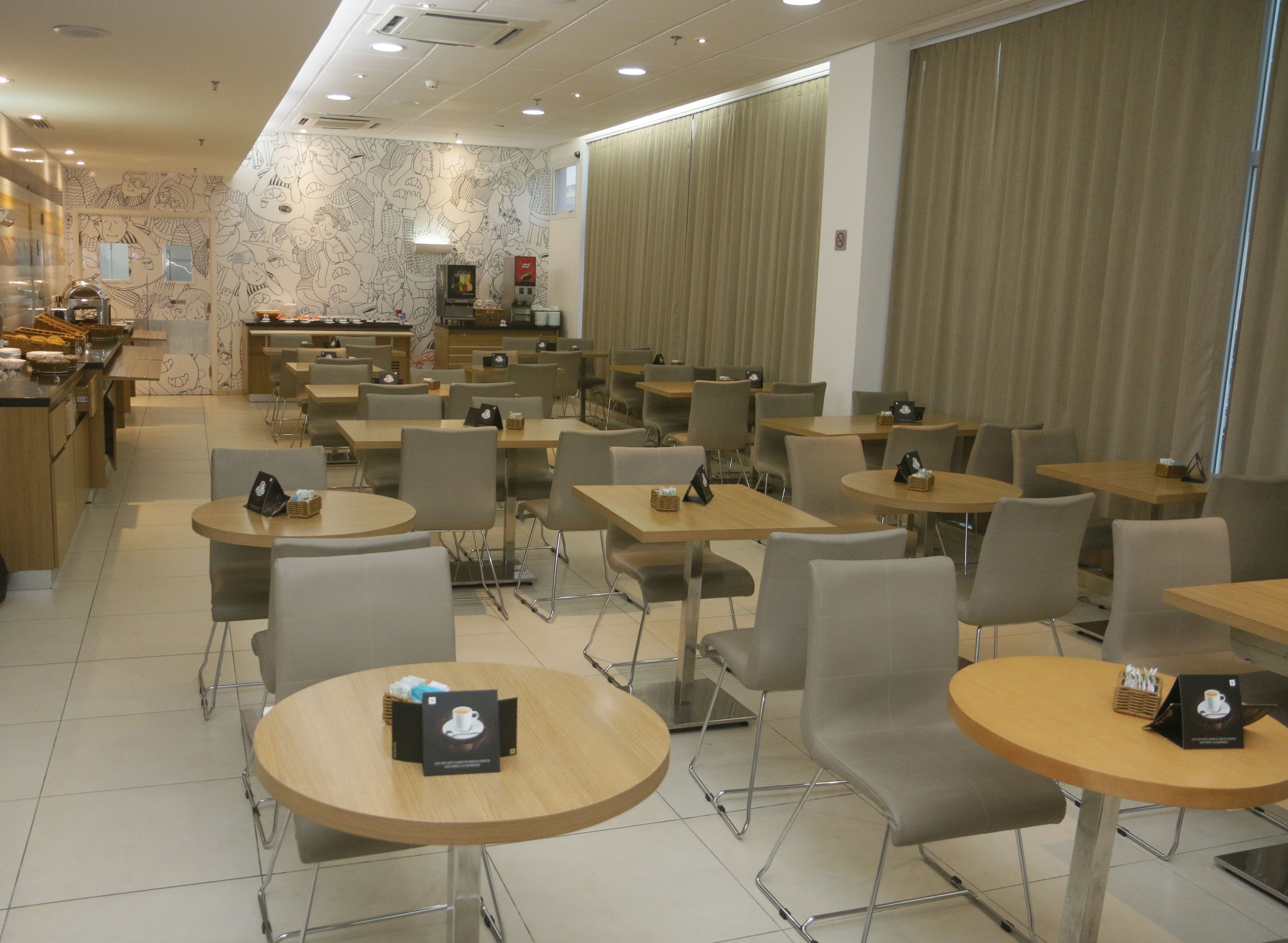 Um café moderno com mesas e cadeiras redondas, uma máquina de café e um quadro de cardápio.