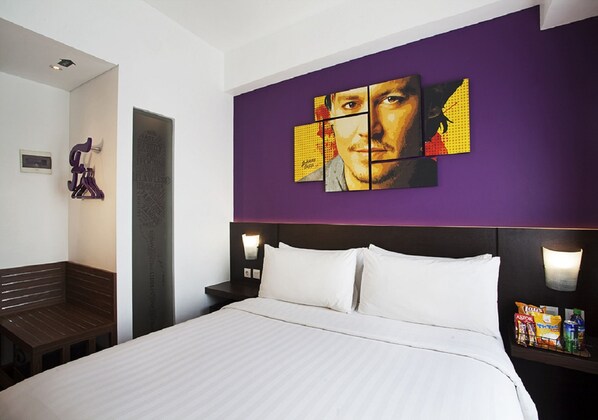 Quarto de hotel com cama, mesa de cabeceira, uma obra de arte na parede e um banco.