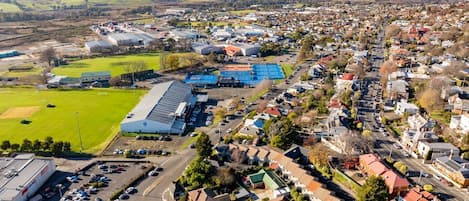 Vista aérea de uma cidade com uma extensa área industrial, casas residenciais e um campo verde.