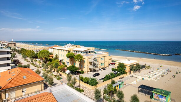 Hotel à beira-mar com vista para a praia, vários andares e estacionamento.
