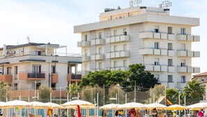 Um edifício com várias andares, varandas e um letreiro no terraço.