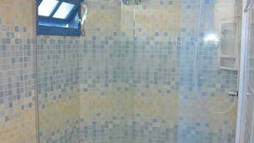Um banheiro com parede em mosaico de azulejos, box para chuveiro e vaso sanitário.