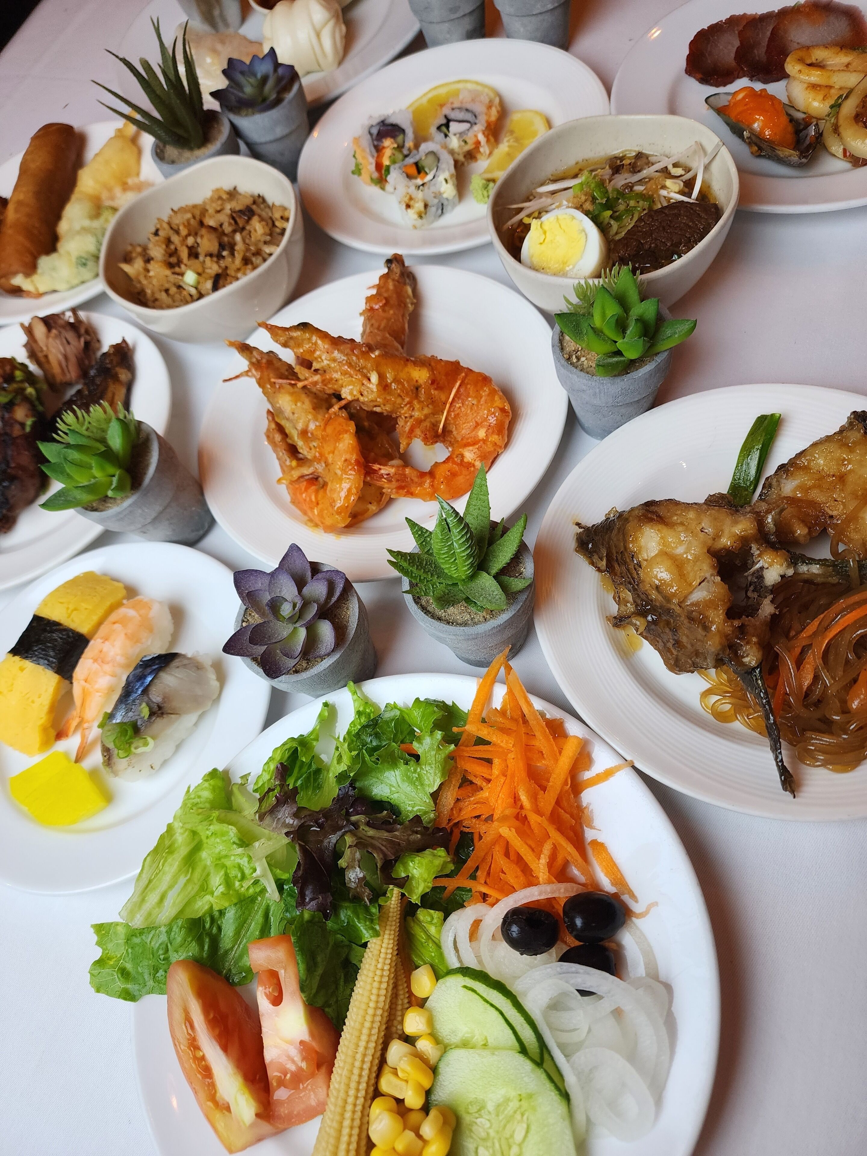 Diversos pratos, incluindo sushi, carnes grelhadas e saladas, dispostos sobre uma mesa.