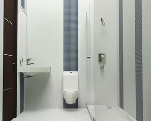 Uma casa de banho moderna com sanita, lavatório e chuveiro.