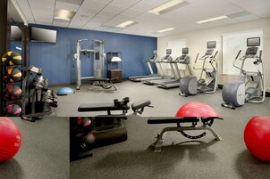 Uma academia com esteiras, elípticos, pesos livres e bolas de exercício.