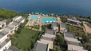 Um resort com duas piscinas, vilas na praia e vista para o oceano.