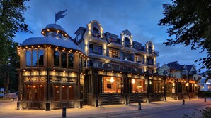 Um edifício de vários andares com um bar e café bem visíveis no andar térreo, com grandes janelas e uma estrutura em forma de cúpula.