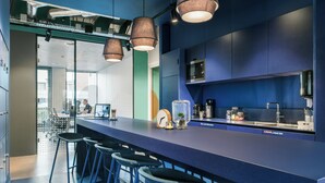 Cozinha moderna com bancada azul, banquetas e iluminação pendente.