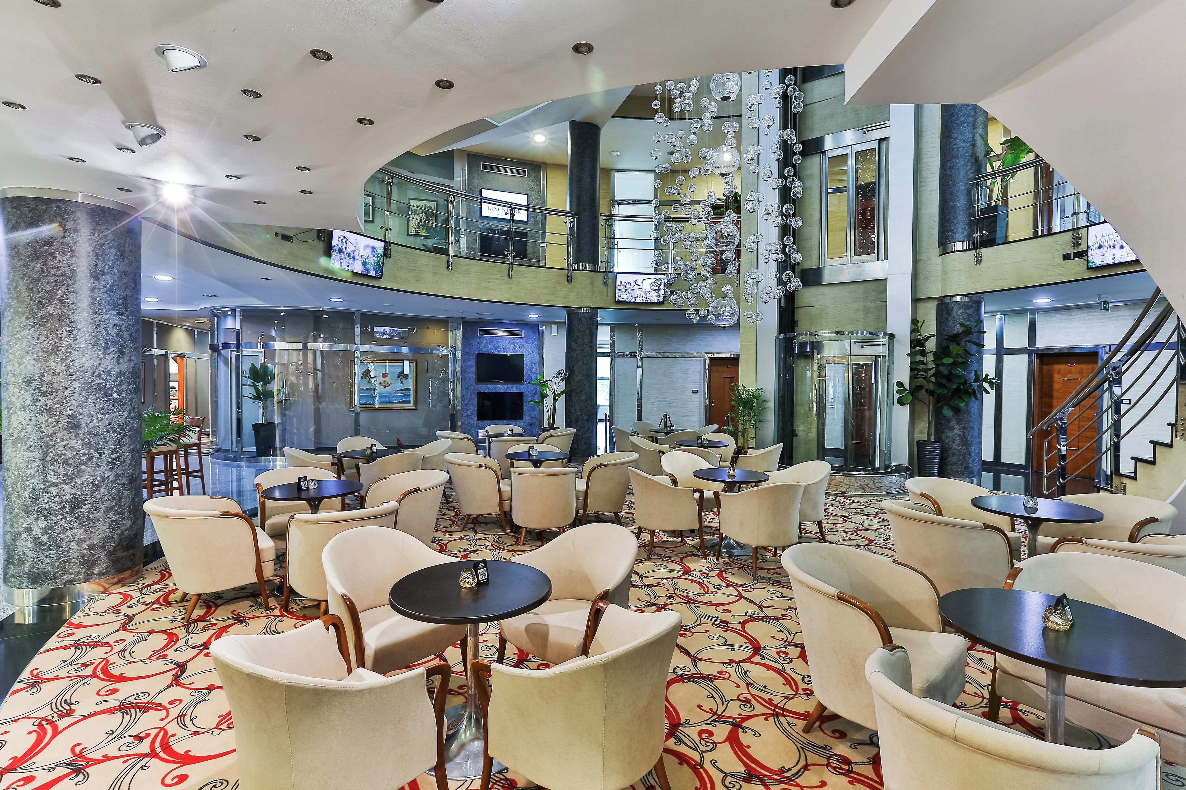 Um hall de hotel com vários níveis, áreas de estar, uma escadaria e uma instalação decorativa em formato de bolhas.