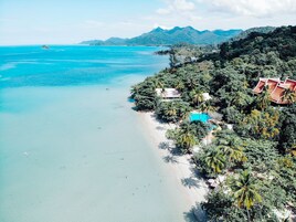 Na praia, areia branca, espreguiçadeiras, guarda-sóis 