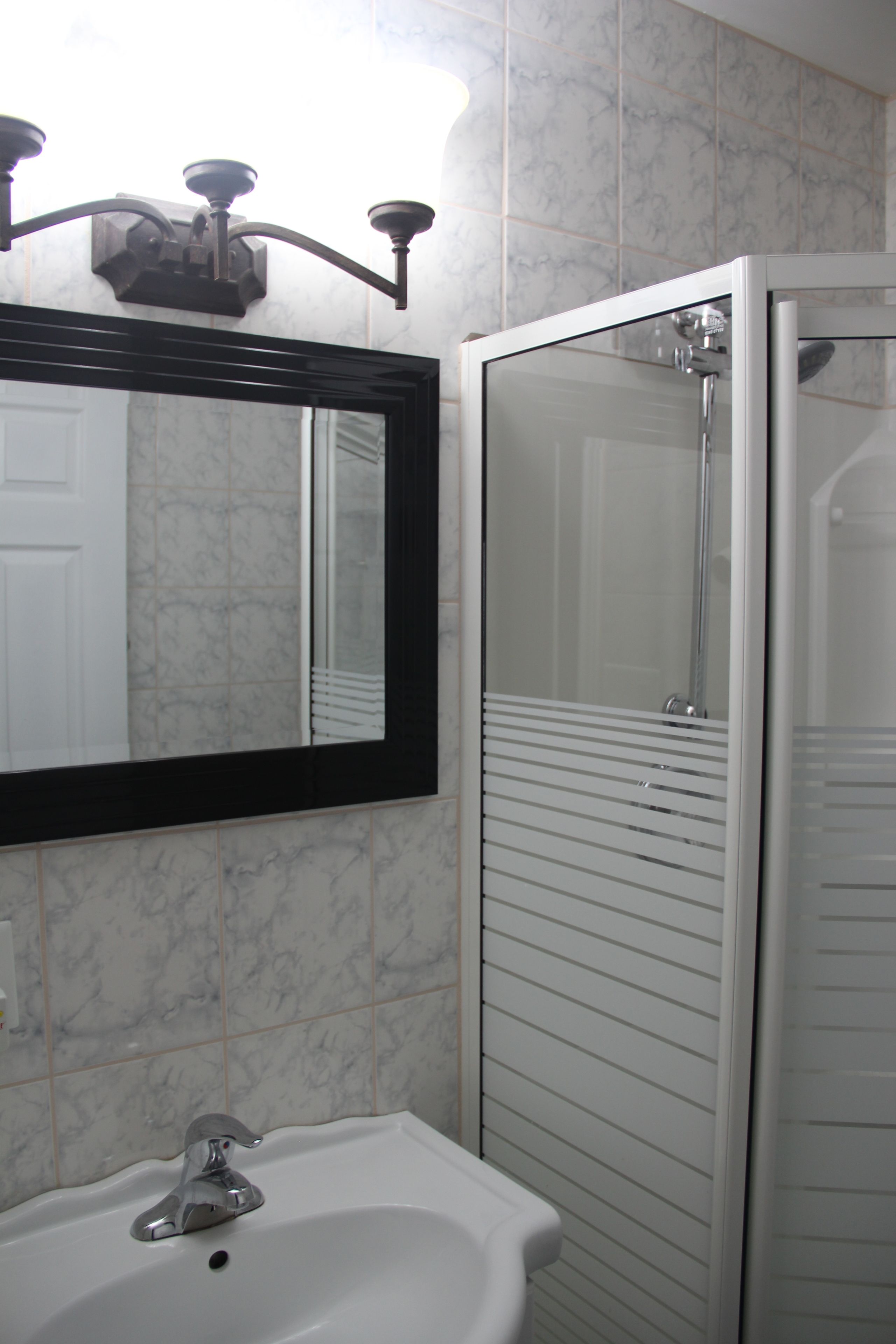 Casa de banho com lavatório branco, espelho e cabine de duche.