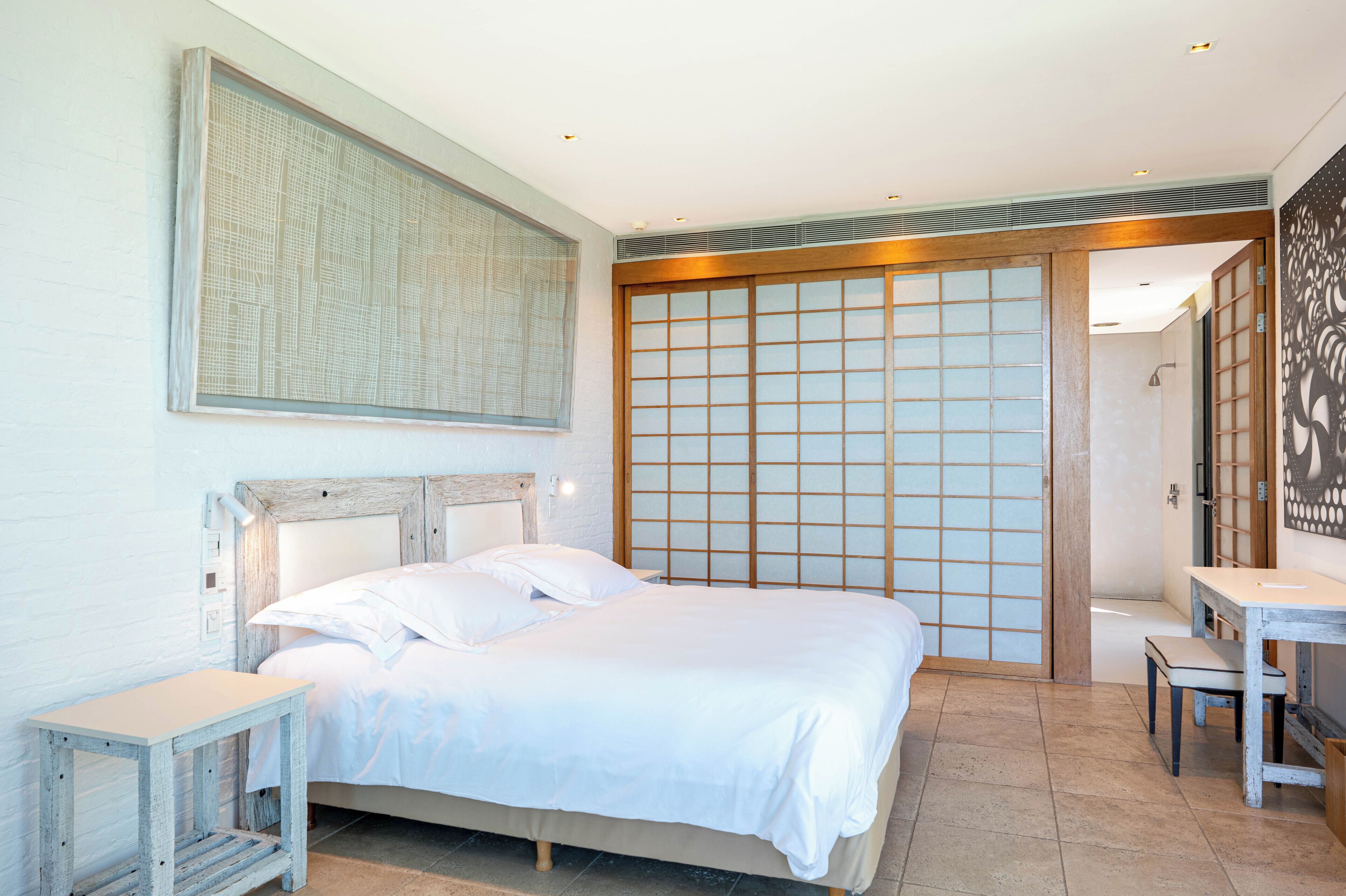 Quarto com cama, mesa de cabeceira e porta de correr estilo shoji.