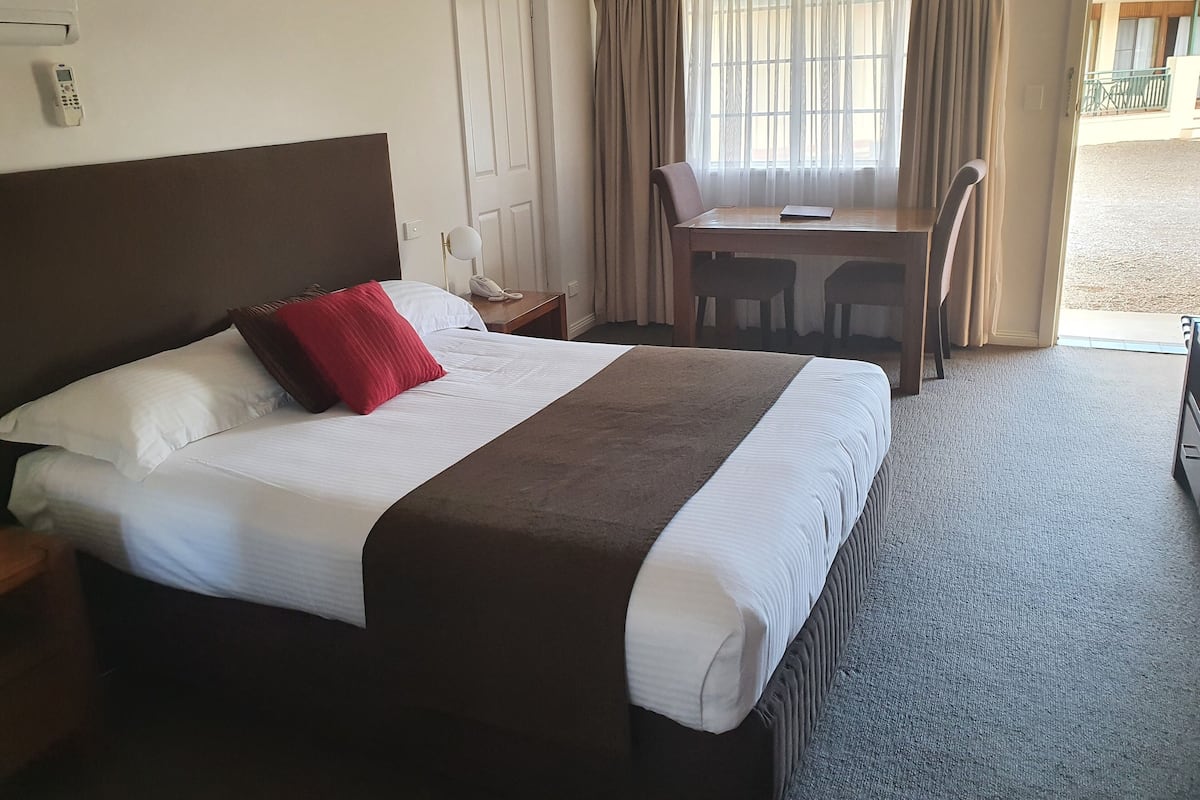 Quarto de hotel com uma cama grande, uma escrivaninha e uma cadeira.