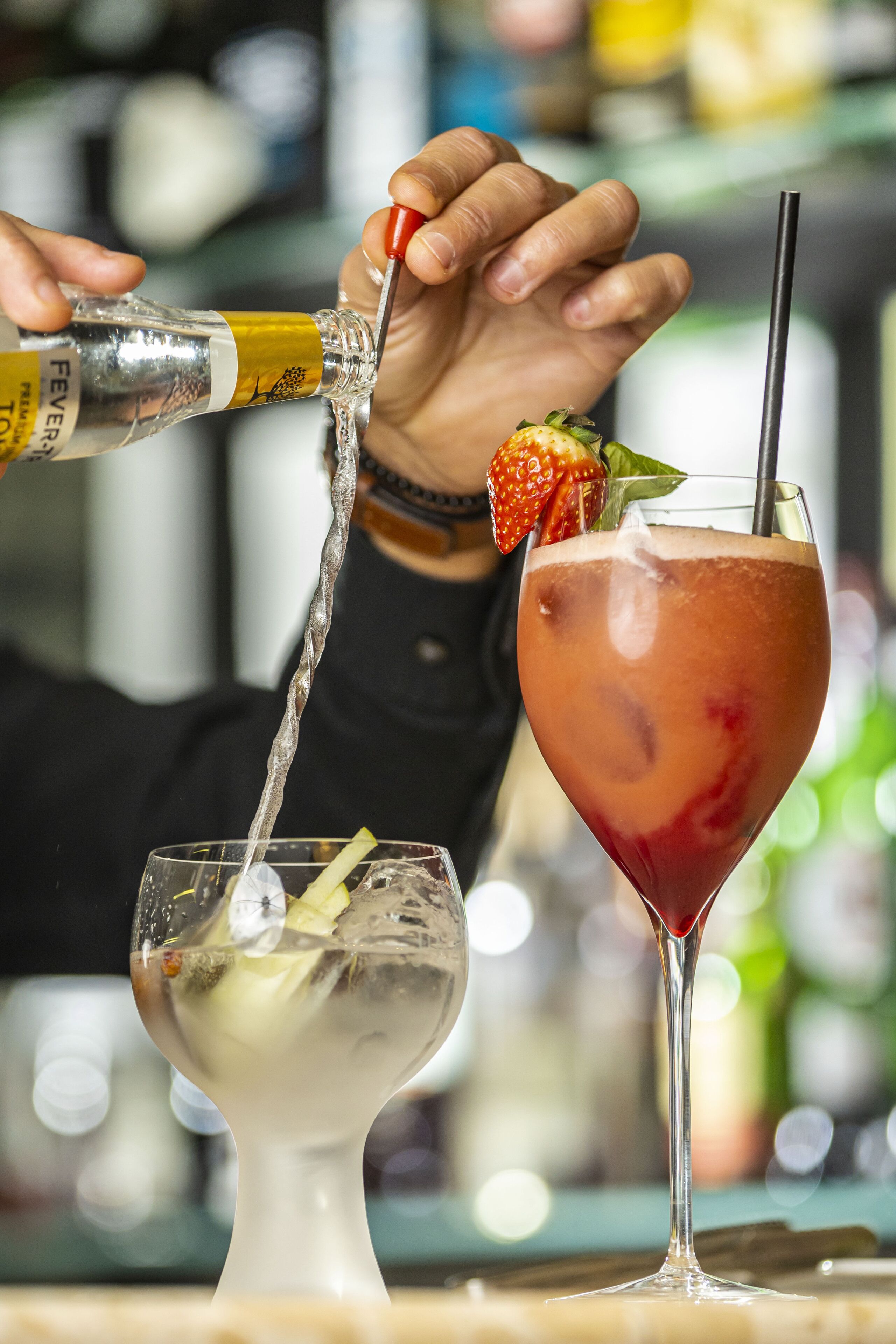 Um bartender servindo uma bebida em um copo com morango.