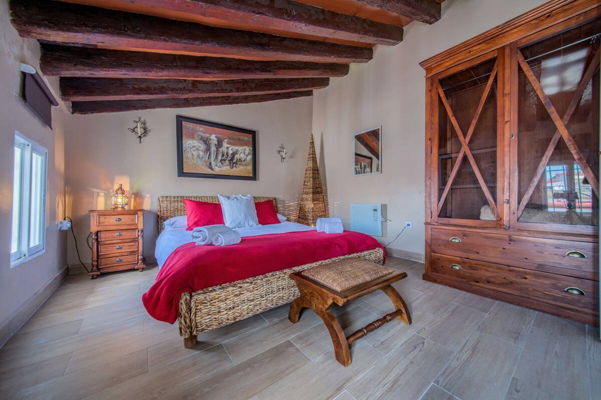 Quarto com cama grande, móveis de madeira e um armário decorativo.