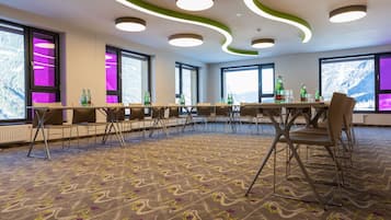 Sala de conferência com uma mesa comprida, cadeiras e grandes janelas com vista para as montanhas.