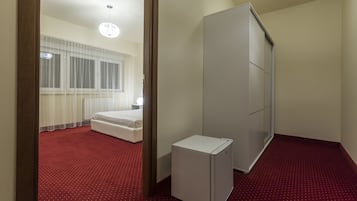 Quarto de hotel com uma cama, um frigorífico pequeno branco e um guarda-roupa.