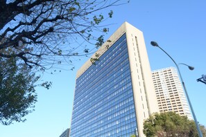 Um edifício alto com fachada de vidro e seção superior bege.