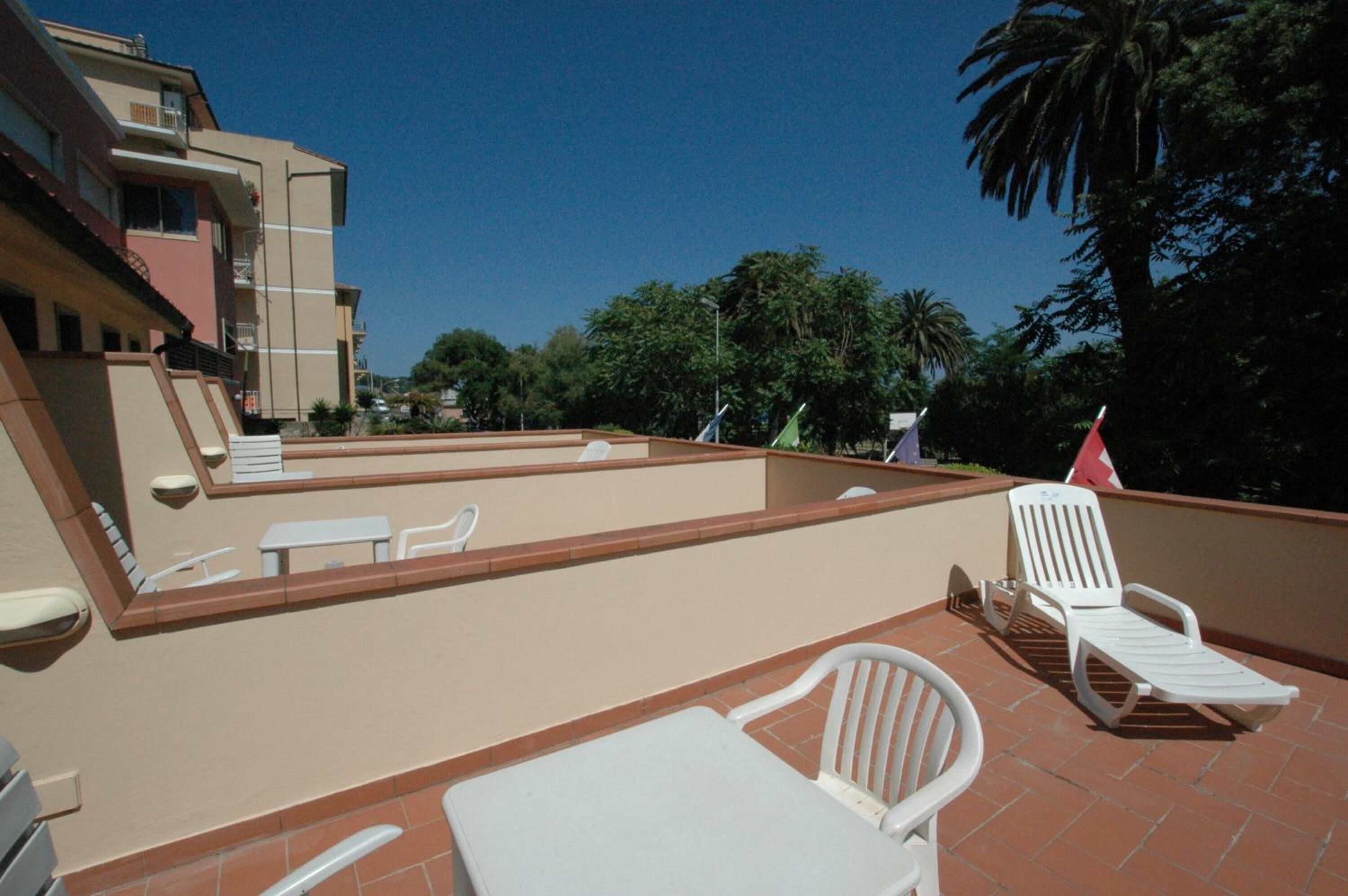 Um terraço no telhado com cadeiras de lounge brancas, uma mesa e uma pequena área de piscina.