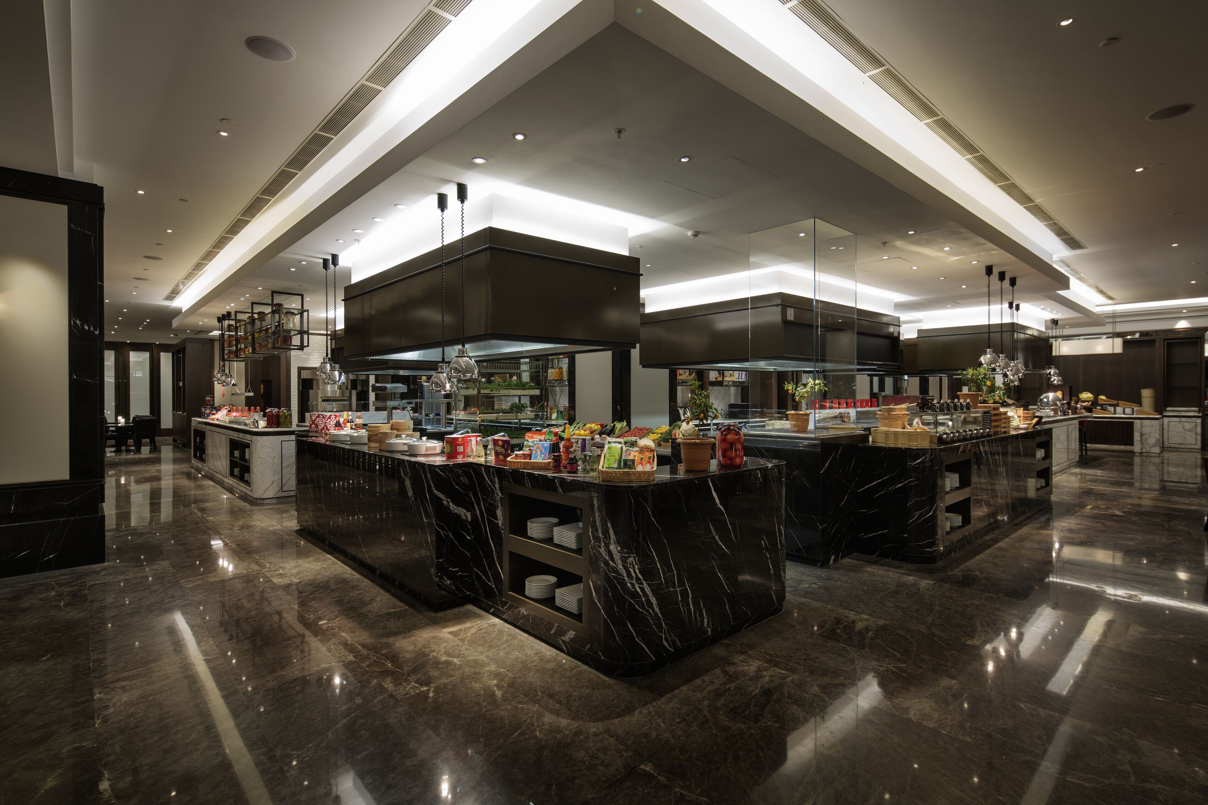 Uma cozinha moderna com bancadas de mármore, uma ilha central com alimentos e um teto alto com iluminação embutida.