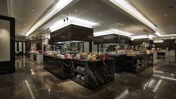 Uma cozinha moderna com bancadas de mármore, uma ilha central com alimentos e um teto alto com iluminação embutida.