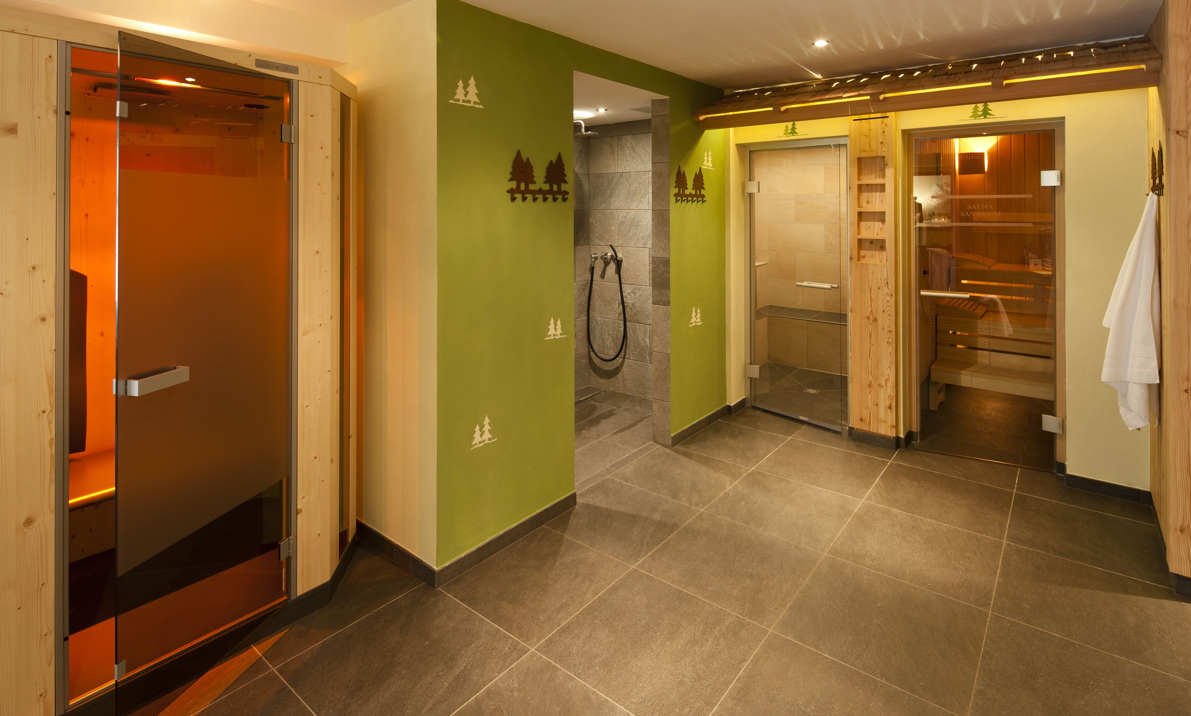 Uma sala de sauna com porta de vidro, área de chuveiro com divisória de vidro e banco de madeira para sauna.