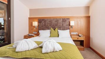 Quarto de hotel com uma cama, duas mesas de cabeceira, uma luminária e vista para o exterior.