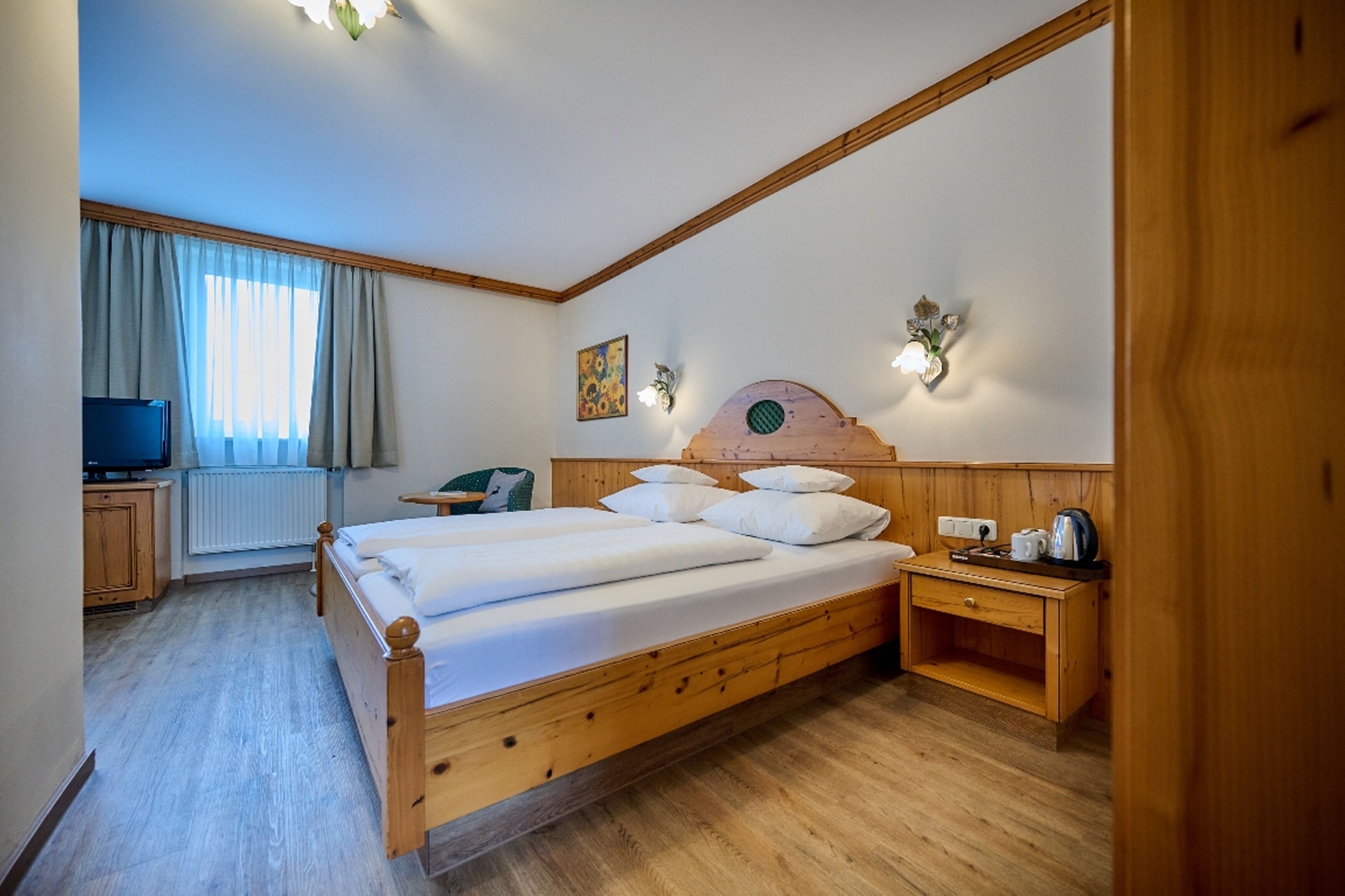 Uma cama de madeira com roupa de cama branca num quarto com soalho e paredes de madeira.