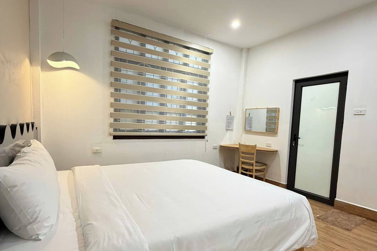 Quarto com cama, mesa de cabeceira e escrivaninha com cadeira.