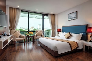 Quarto de hotel com uma cama grande, uma escrivaninha, uma cadeira, uma televisão e vista para a cidade.