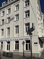 Um edifício de vários andares com uma placa que diz 'HOTEL LA GLOCHE'.