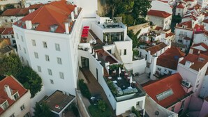 Um edifício moderno com vários andares, varandas e um terraço no telhado.
