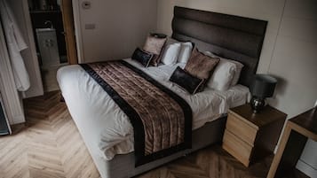 Quarto moderno com uma cama grande, uma mesa de cabeceira de madeira e um espelho.