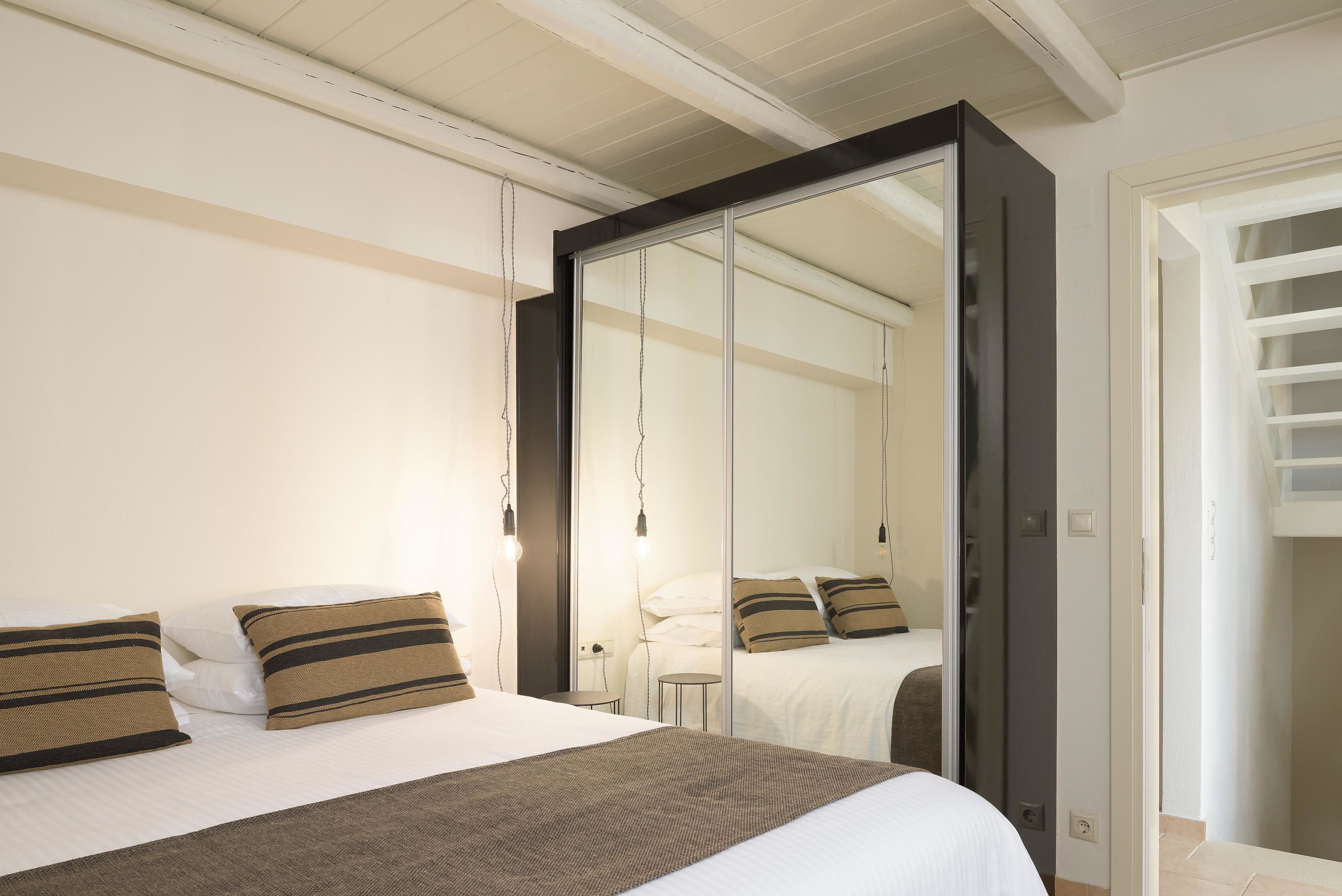 Quarto de hotel com uma cama, espelho e guarda-roupa.