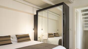 Quarto de hotel com uma cama, espelho e guarda-roupa.