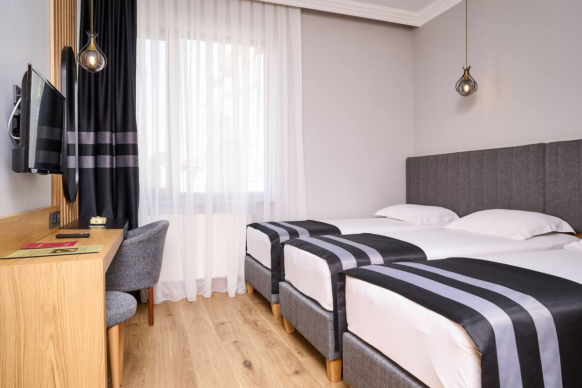 Quarto de hotel com duas camas, uma escrivaninha e uma cadeira.