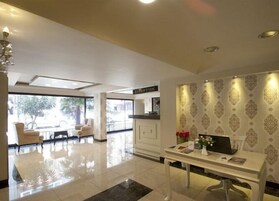 Área de recepção de hotel com balcão, cadeiras e vista para o exterior.