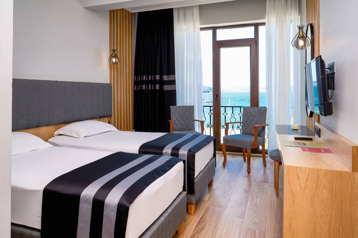 Quarto de hotel com duas camas, uma escrivaninha, uma cadeira e uma televisão.