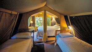 Um quarto aconchegante em estilo de tenda, com duas camas, uma janela e um abajur.