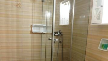 Casa de banho com cabine de duche em vidro, sanita e lavatório.
