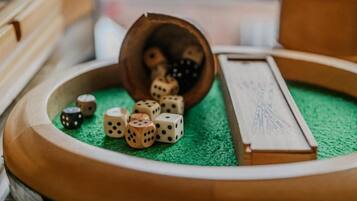 Jogo de tabuleiro de madeira com dados e livro de regras sobre um feltro verde.
