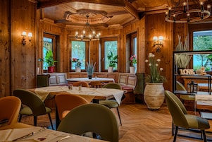 Um interior de madeira com mesas, cadeiras e um candelabro.