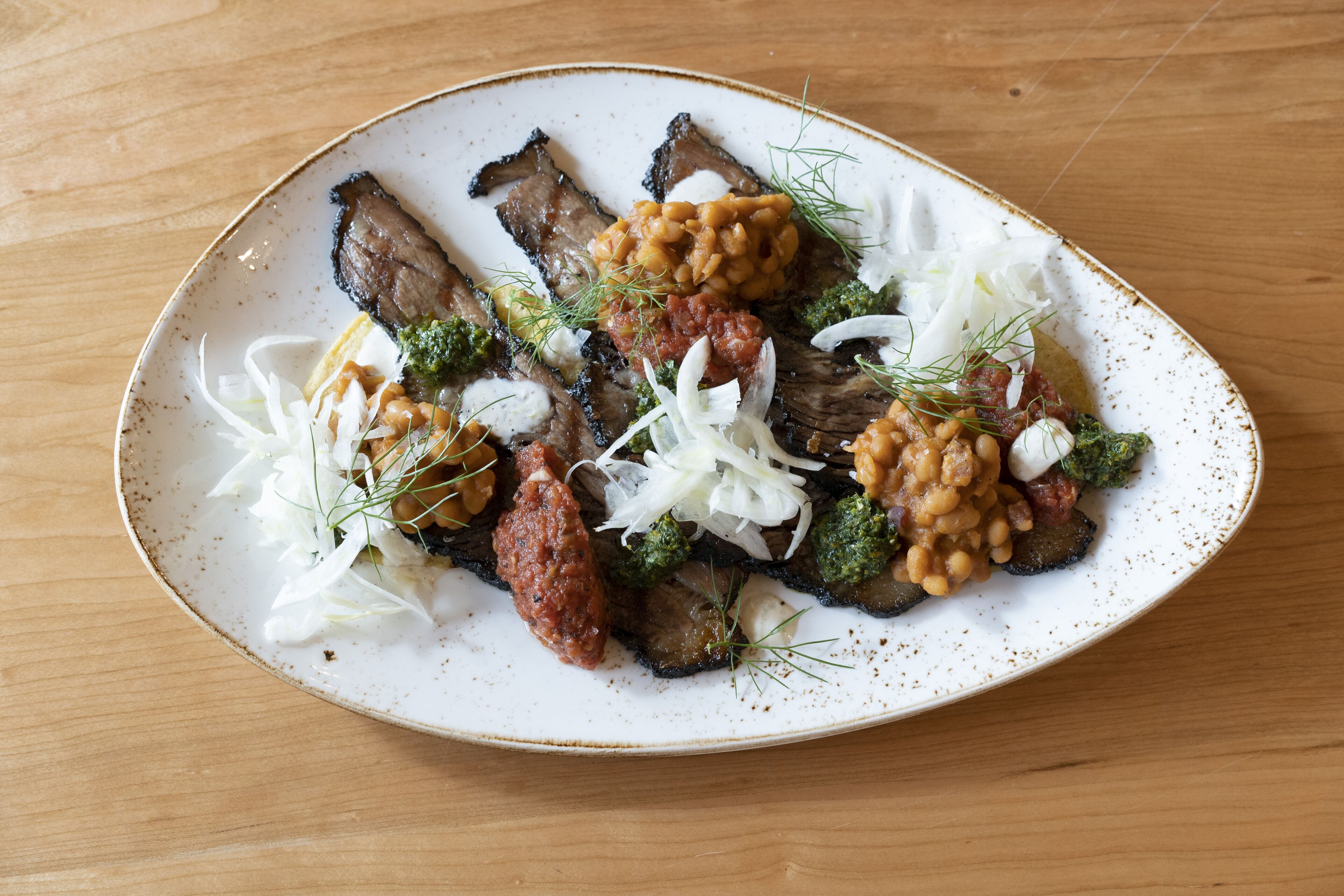 Um prato de comida com diversos ingredientes, incluindo carne, feijão e legumes.