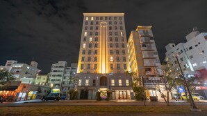 Um hotel de vários andares com entrada central e fachada bem iluminada.