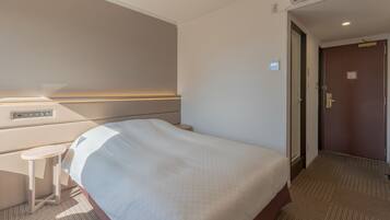 Quarto de hotel com cama, mesa de cabeceira e porta.