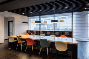 Sala de conferências moderna com uma mesa comprida, várias cadeiras e iluminação pendente.