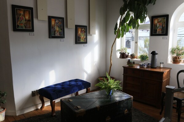 Um quarto com um banco azul, um armário de madeira e uma mesa com uma planta.